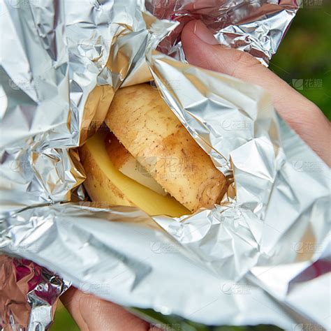 用锡纸包裹的土豆和培根，在篝火上烤