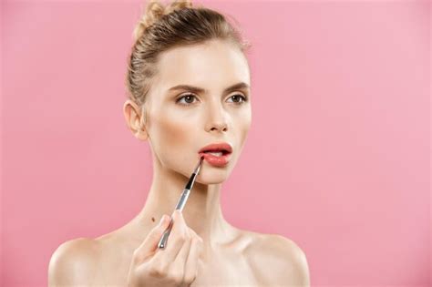 Premium Photo Close Up Of Young Woman Applying Lipstick Against Pink