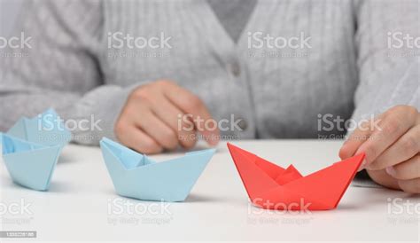 파란색 종이 보트 무리가 흰색 배경 앞에서 빨간 배를 따라갑니다 대중을 조작하는 팀의 강하고 카리스마 있는 지도자의 개념 개념에