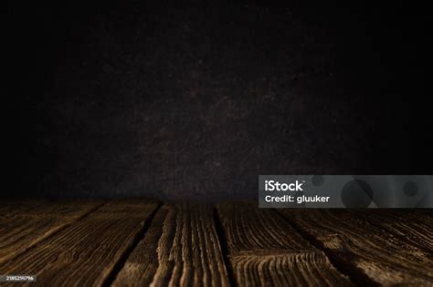 낡은 질감의 널빤지로 만든 빈 나무 테이블 표면은 밝은 그라데이션이 있는 회색의 흐릿한 벽에 대비합니다 선택적 초점 및 복사 공간이 있는 수평 제품 디스플레이를 위한 어두운