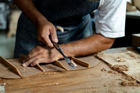 Close Up Of Guitar Luthier Using Chisel To Shave Bracing Of Acoustic