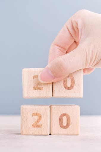 추상 2020 및 2019 새해 카운트 다운 디자인 개념 나무 테이블과 파란색 배경에 나무 블록 큐브를 들고 여자 12월 31
