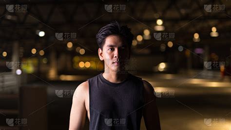 年轻英俊的亚洲男人在晚上在户外思考的肖像