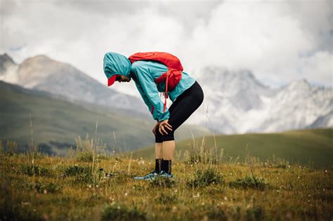 피곤한 여자 트레일 러너가 배경에 눈 덮인 산과 함께 초원에서 달리고 있습니다 40 44세에 대한 스톡 사진 및 기타 이미지 40 44세 건강한 생활방식 검은색