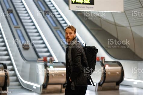 공항 터미널이나 기차역의 에스컬레이터 배경에 배낭을 메고 있는 수염 난 남자 관광객의 초상화 25 29세에 대한 스톡 사진 및