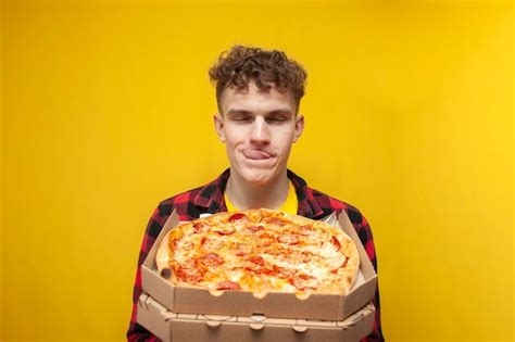 Premium Photo Curly Cute Guy Sniffs Pizza And Licks His Lips On A