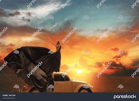 زن جوان با لباس لوکس بلند زیبا در مقابل غروب دریا 1647769