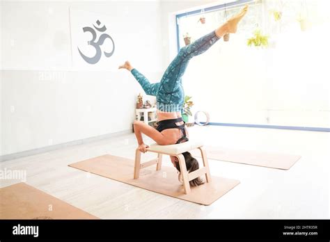 Fit Woman In Headstand Using A Professional Yoga Bench Feet Up Barefoot With Legs Split Wide