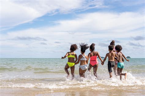 아프리카계 미국인 어린이 또는 형제 자매의 그룹은 수영 복을 입고 학교 또는 가족에서 휴일이나 여름 동안 재미와 함께 바다로 손을 운반 건강한 생활방식에 대한 스톡 사진 및