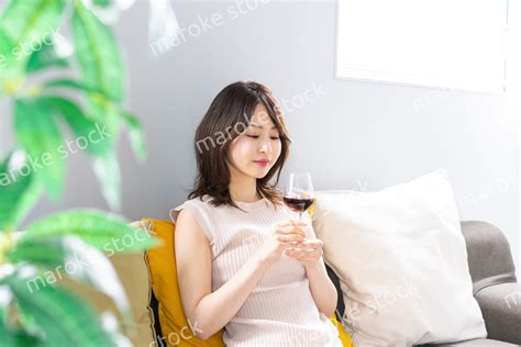 家でワインを楽しむ若い女性 Maroke Stock｜写真素材をフォトグラファーから直接購入できるストックフォトサイト