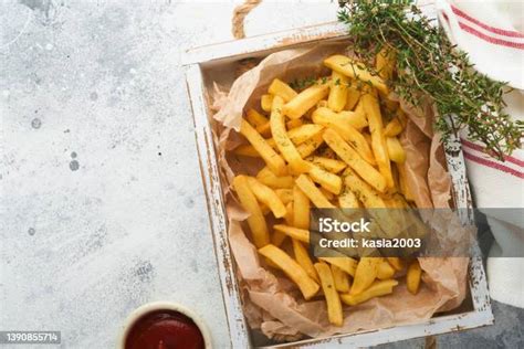 감자 튀김 오래된 회색 콘크리트 배경에 토마토와 치즈 소스를 곁들인 나무 커팅 보드의 양피지 종이에 맛있는 프렌치 프라이 서버 다양한 케토 요리 패스트 푸드 건강에 해로운