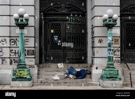 A Homeless Man Seems To Be Passed Out On The Steps Of The Vandalized