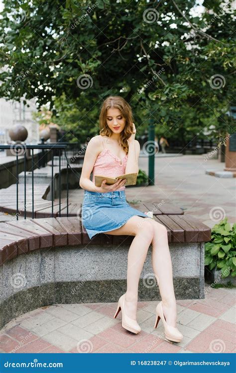 Jonge Meid In Zomerkleren Met Lange Benen Op Een Bank In De Open Lucht