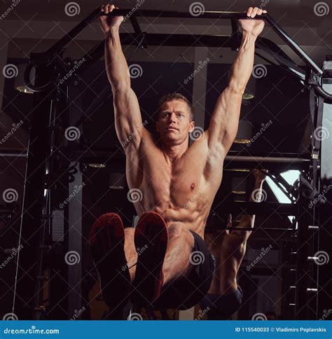 Hombre Descamisado Muscular Que Hace Pectorales En La Barra Horizontal En El Gimnasio Imagen De