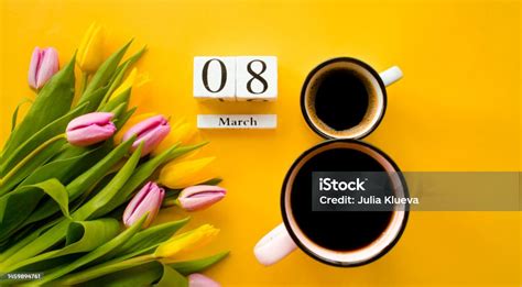 배너숫자 8 모양의 뜨거운 모닝 커피 두 잔과 밝은 노란색 배경에 노란색 라일락 튤립 꽃다발 위에서 본 모습 텍스트 공간을 복사합니다 휴일의 개념 International