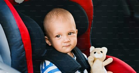 귀여운 어린 소년이 차 안의 카시트에 앉아 밖을 내다보고 있다 사진 Unsplash의 수송 이미지