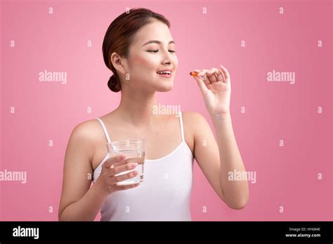 Young Asian Beauty Young Woman Eating Pills And Drinking Water On Pink