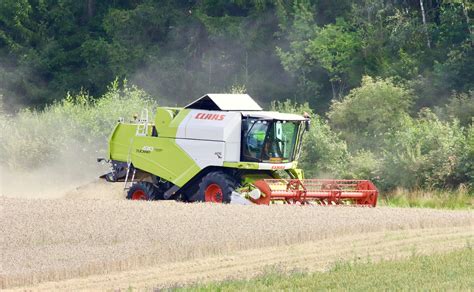 A Green And White Combine Is Driving Through A Field Photo Free