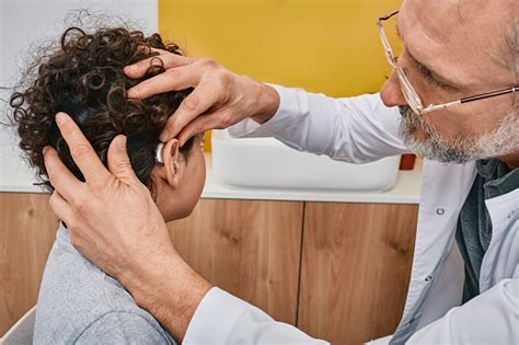 청각 학자는 청각 클리닉을 방문하는 동안 남성 어린이 귀에 보청기에 적합합니다 어린이를 위한 청력 솔루션 보청기에 대한 스톡