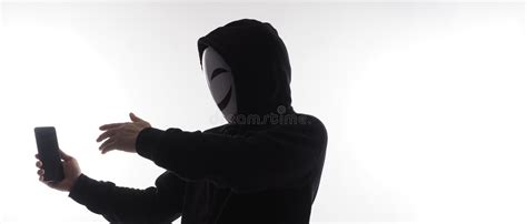 Hacker Anonymous And Face Mask With Smartphone In Hand Stock Image