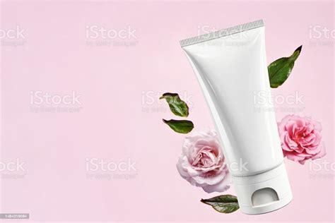 섬세한 분홍색 장미가 있는 분홍색 배경에 흰색 빈 화장품 튜브 장미 추출물 또는 스킨 케어가 함유 된 천연 화장품 플랫 레이