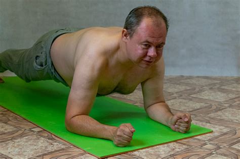 뚱뚱한 중 년 남자 스포츠 하 고 바닥에 녹색 매트에 집에서 체중 감량을 위한 체조를 하 고 건강관리와 의술에 대한 스톡 사진