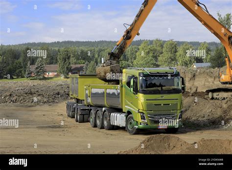 Tracked Excavator Loading Soil Onto Green Volvo Fh16 Truck Cassette