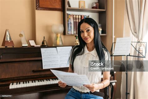 Young Woman Looking At The Musical Sheet Before Playing The Piano At