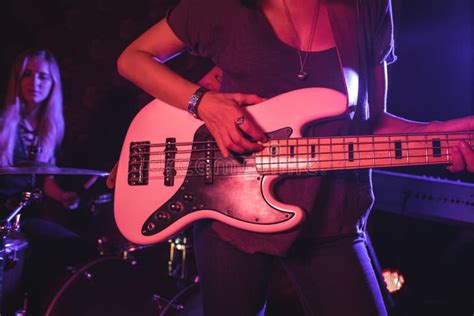 Female Guitarist Playing Guitar With Drummer In Nightclub Stock Image