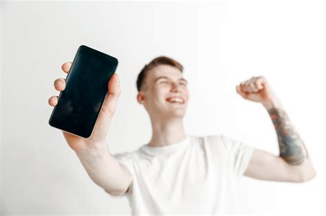 스마트 폰 화면과 서명 Ok 회색 배경에 고립 보여주는 젊은 잘생긴 남자 가리키기에 대한 스톡 사진 및 기타 이미지 가리키기