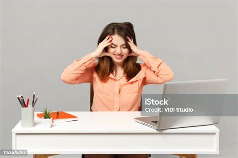 눈을 감고 머리에 손을 넣어 젊은 소진 여자 회색 배경에 고립 된 Pc 노트북으로 흰색 책상에서 작업을 앉아 성취 비즈니스