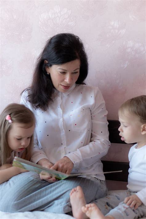 Grandmother With Grandson And Granddaughter In Bed Reading A Book