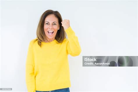 아름 다운 중 년 여자는 분노 하 고 좌절 하 고 분노와 함께 외치는 동안 분노 주먹 모금 미친 격리 된 배경 위에 노란색 스웨터를 입고 분노와 공격적 개념 갈색 머리에