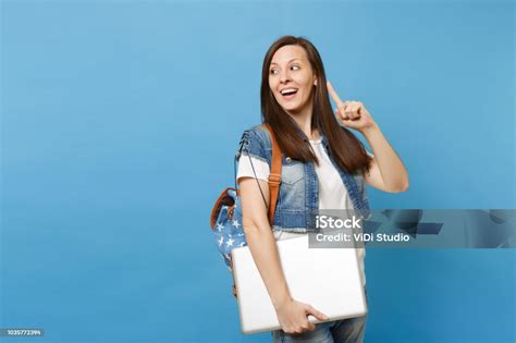 젊은 배낭 들고 파란색 배경에 고립 된 노트북 Pc 컴퓨터를 새로운 아이디어 포인팅 검지 손가락을 데 귀여운 여자 학생을 흥분