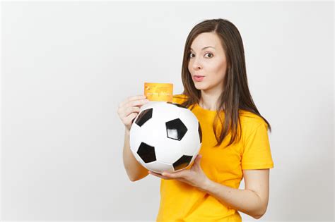 아름 다운 유럽 젊은 명랑 한 여자 축구 팬 또는 선수 신용 카드 축구공을 들고 노란색 유니폼에 흰색 배경에 고립 스포츠 축구