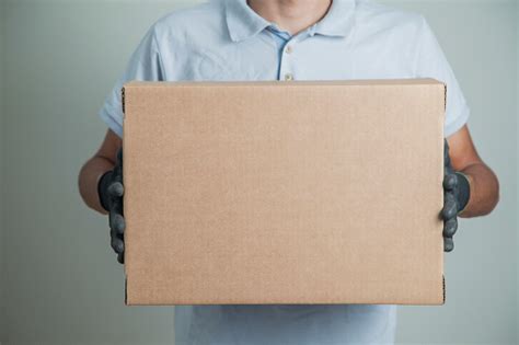 회색 배경에 제품을 제공하기위한 골판지 상자를 들고 검은 장갑을 가진 남자의 세부 사항 Store Opening에 대한 스톡 사진 및 기타 이미지 Store