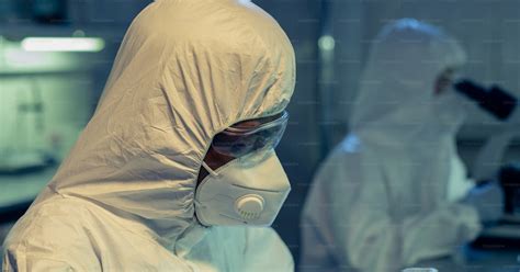 동료와 함께 위험한 화학 샘플로 테이블에서 작업하는 보호 작업복을 입은 과학자 사진 Unsplash의 실내 이미지