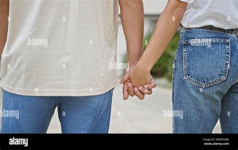 A Couple Holds Hands Affectionately On A City Street Symbolizing Love