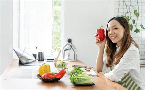 젊은 아름다운 여자는 부엌 방에서 신선한 야채와 과일로 건강 식품을 요리합니다 미소 지으며 카메라를 바라보고 있습니다 여자에