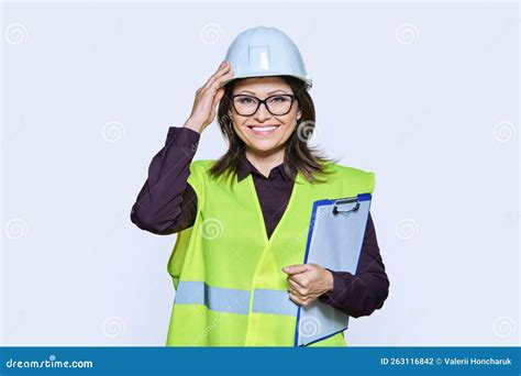 Professional Woman In Safety Vest Helmet Holding Clipboard On White