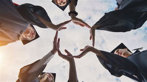 Graduate Students In Black Robes And Caps Make A Circle Shape From