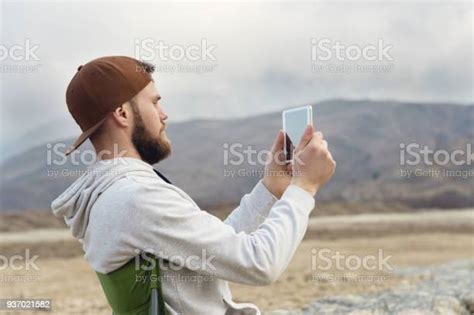 모자에 수염 Hipster와 그의 손에 태블릿 셔츠 사진을 찍는 태블릿에는 호수에 의해 자연에 있는 동안 경관에 대한 스톡 사진