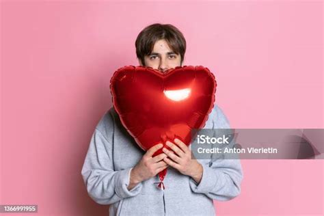 분홍색 스튜디오 배경에 고립 된 심장 모양의 빨간 풍선으로 얼굴을 덮고있는 어린 소년의 자른 초상화 20 24세에 대한 스톡 사진 및 기타 이미지 Istock