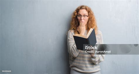 실수 두려움 침묵 비밀 개념에에서 무서 워의 표현에 대 한 수치와 충격 손으로 책 표지 입 읽고 회색 그런 지 벽에 빨강 머리