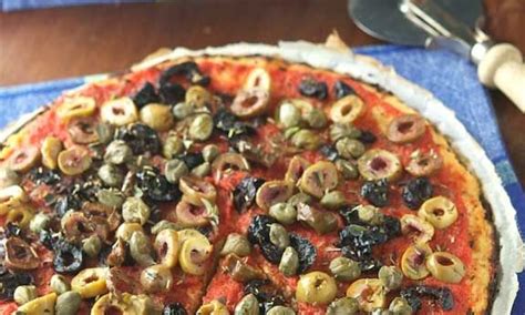 A Pizza Sitting On Top Of A Pan Covered In Olives And Other Toppings