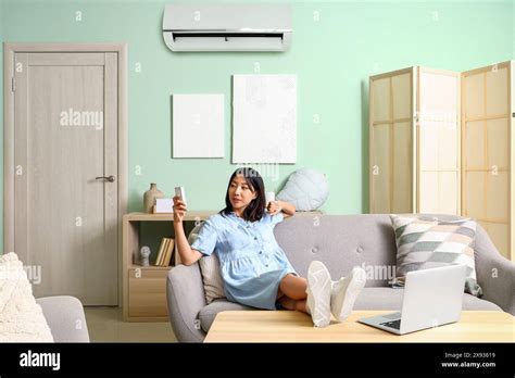 Beautiful Asian Woman Switching On Air Conditioner At Home Stock Photo Alamy