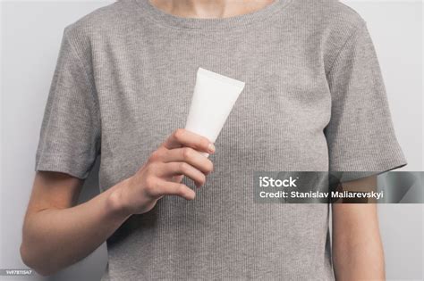 흰색 배경에 격리된 빈 흰색 화장품 튜브 크림을 바른 여성의 손이 화장품 튜브에 닿습니다 크림 핸드 로션의 개념 겨울 피부 관리 튜브에서 핸드 크림을 사용하는 여자 전체