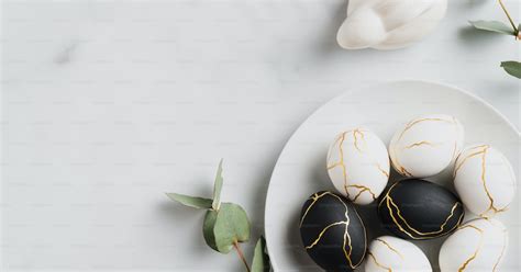 우아한 부활절 플랫 레이 구성 검은 색과 황금색 부활절 달걀 토끼 토끼 유칼립투스 잎은 대리석 배경에 있습니다 복사 공간이 있는 상위 보기입니다 행복한 부활절