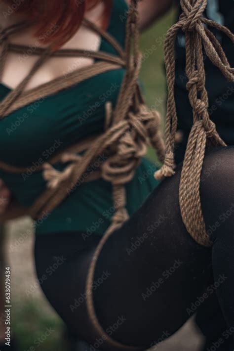 Tied Up Woman In Green Body And Black Tights With A Natural Rope