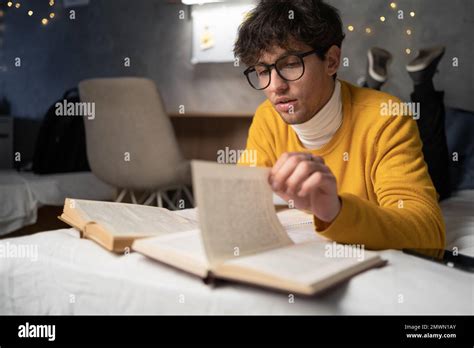 Male College Student Lies On Bed In Shared House Prepare For Exam